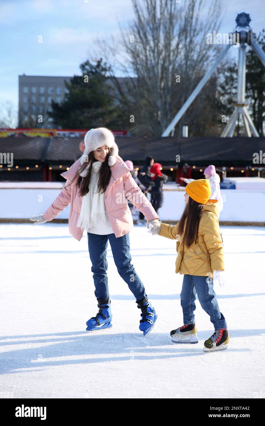 Mother and daughter spending time together at outdoor ice skating rink ...