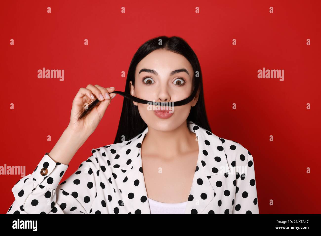 Funny woman making fake mustache with her hair on red background Stock Photo - Alamy