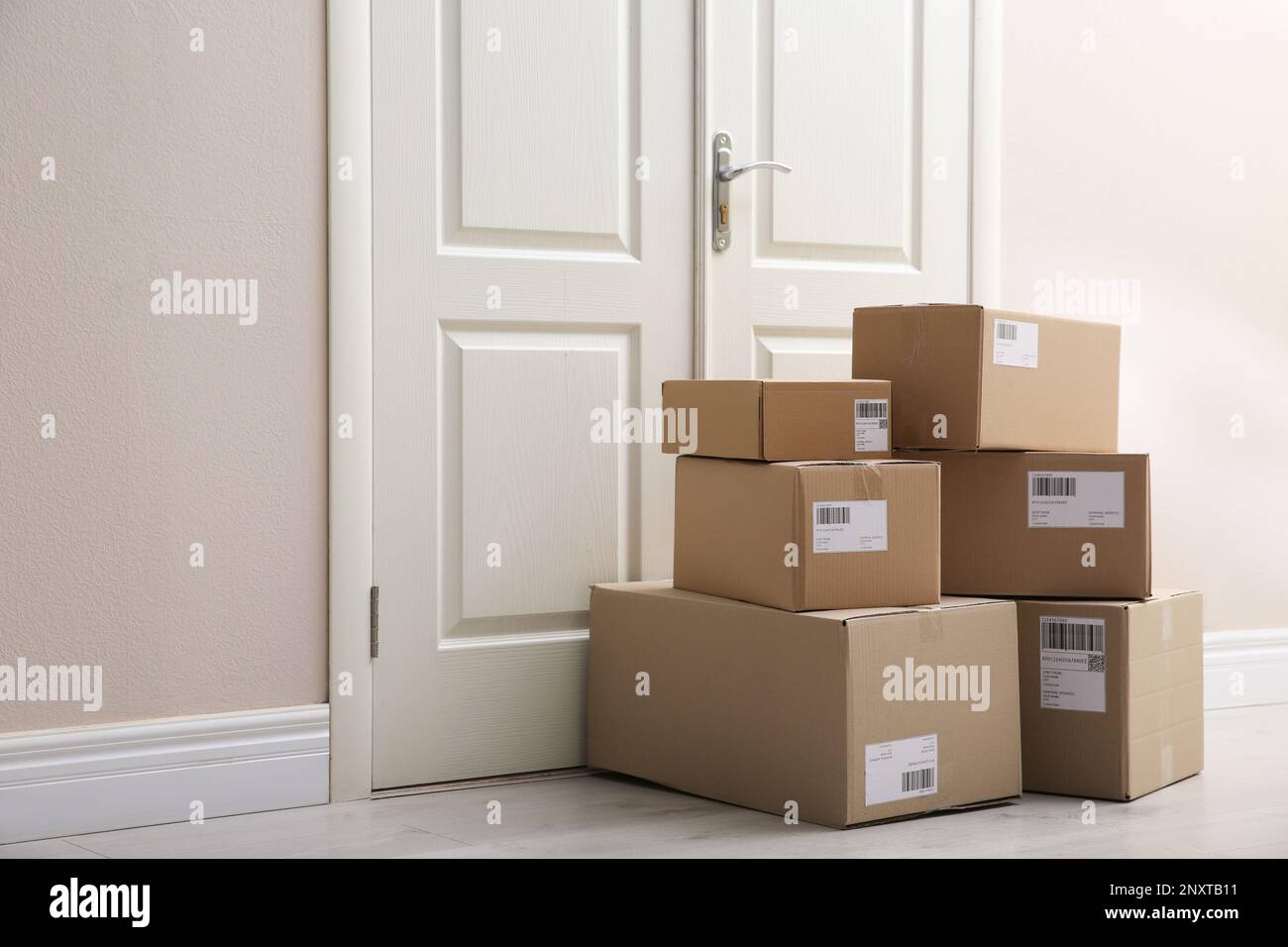 Stacked parcels near door on floor. Delivery service Stock Photo - Alamy