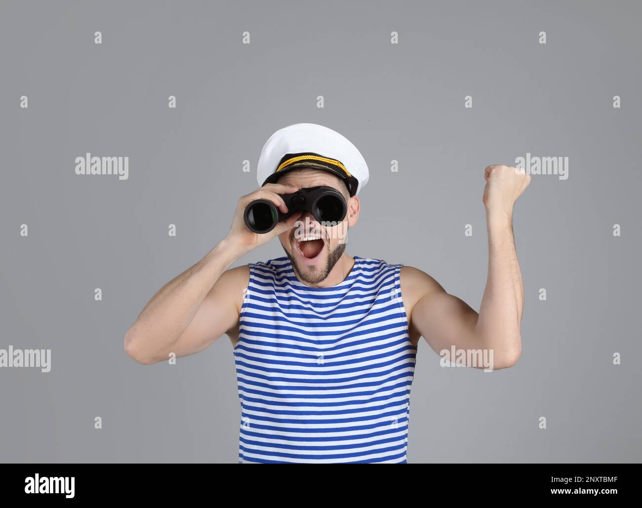 Happy sailor looking through binoculars on grey background Stock Photo ...