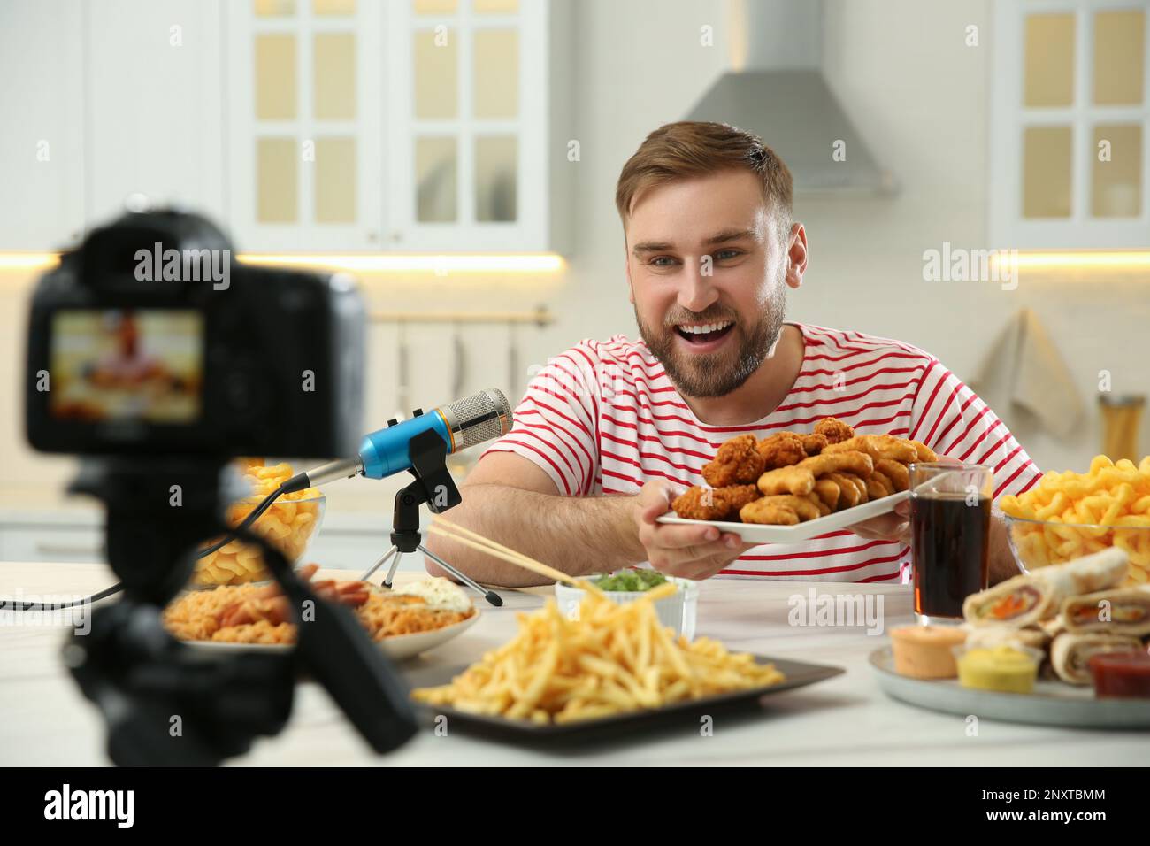 Food blogger recording eating show on camera in kitchen. Mukbang vlog ...