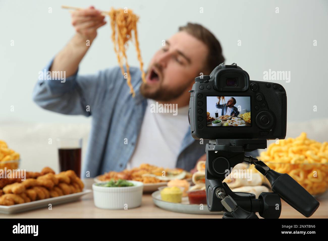 Food blogger recording eating show against light background, focus on ...