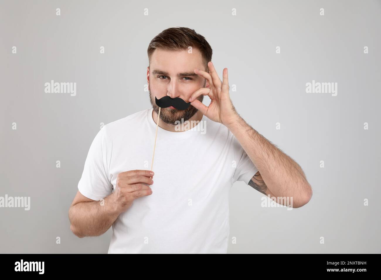 Funny man with fake mustache on light grey background Stock Photo - Alamy