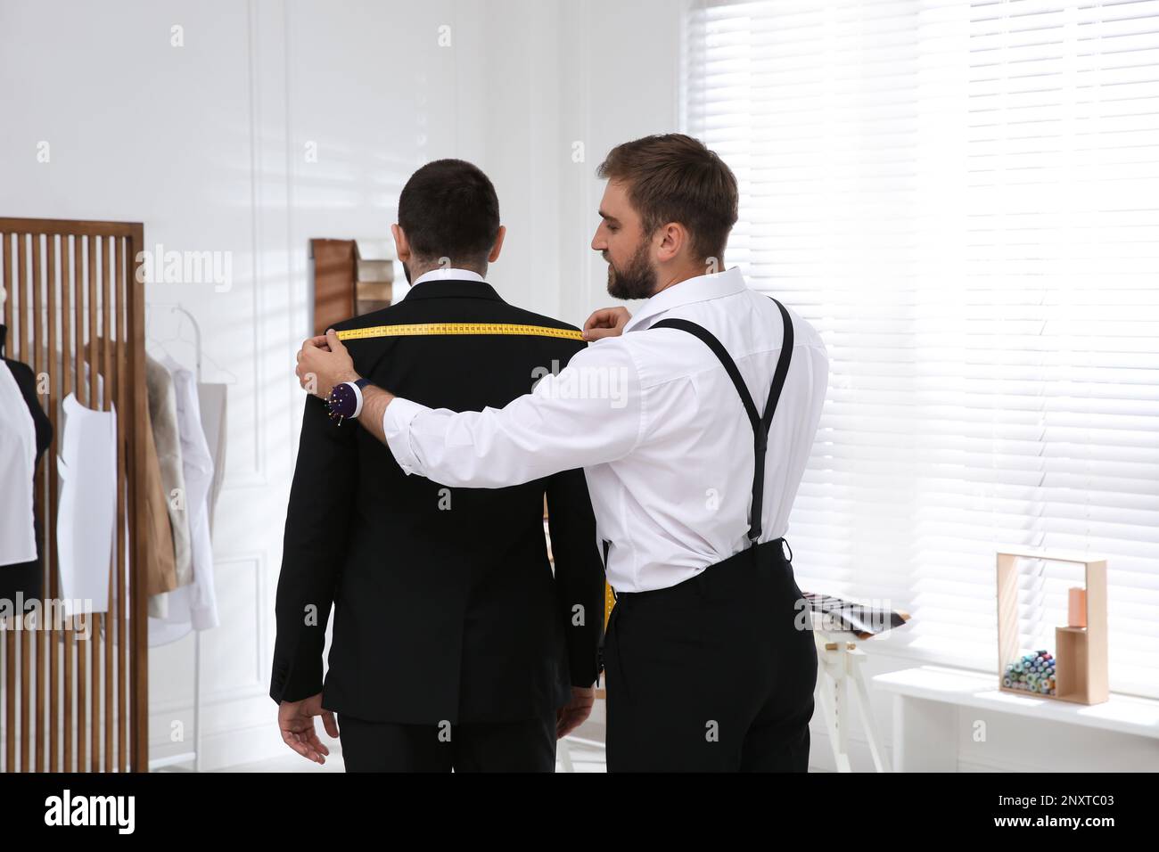 Professional tailor measuring client's shoulder width in atelier Stock ...