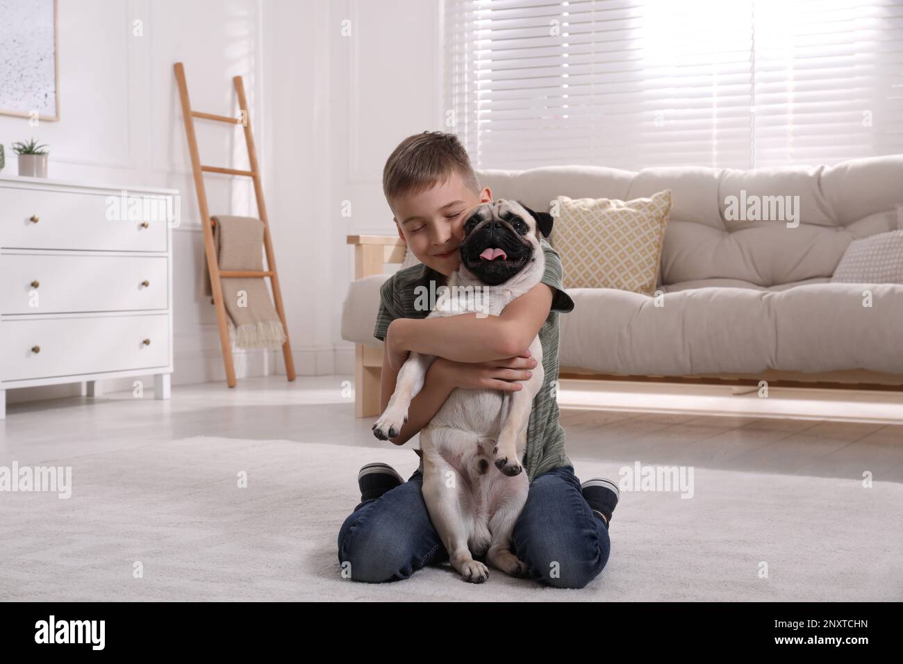 Boy hugging his cute pug in living room Stock Photo - Alamy