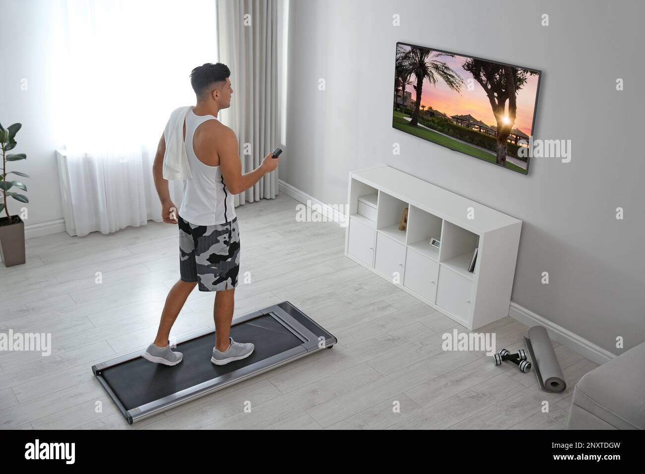 Sporty man with remote control training on walking treadmill and ...