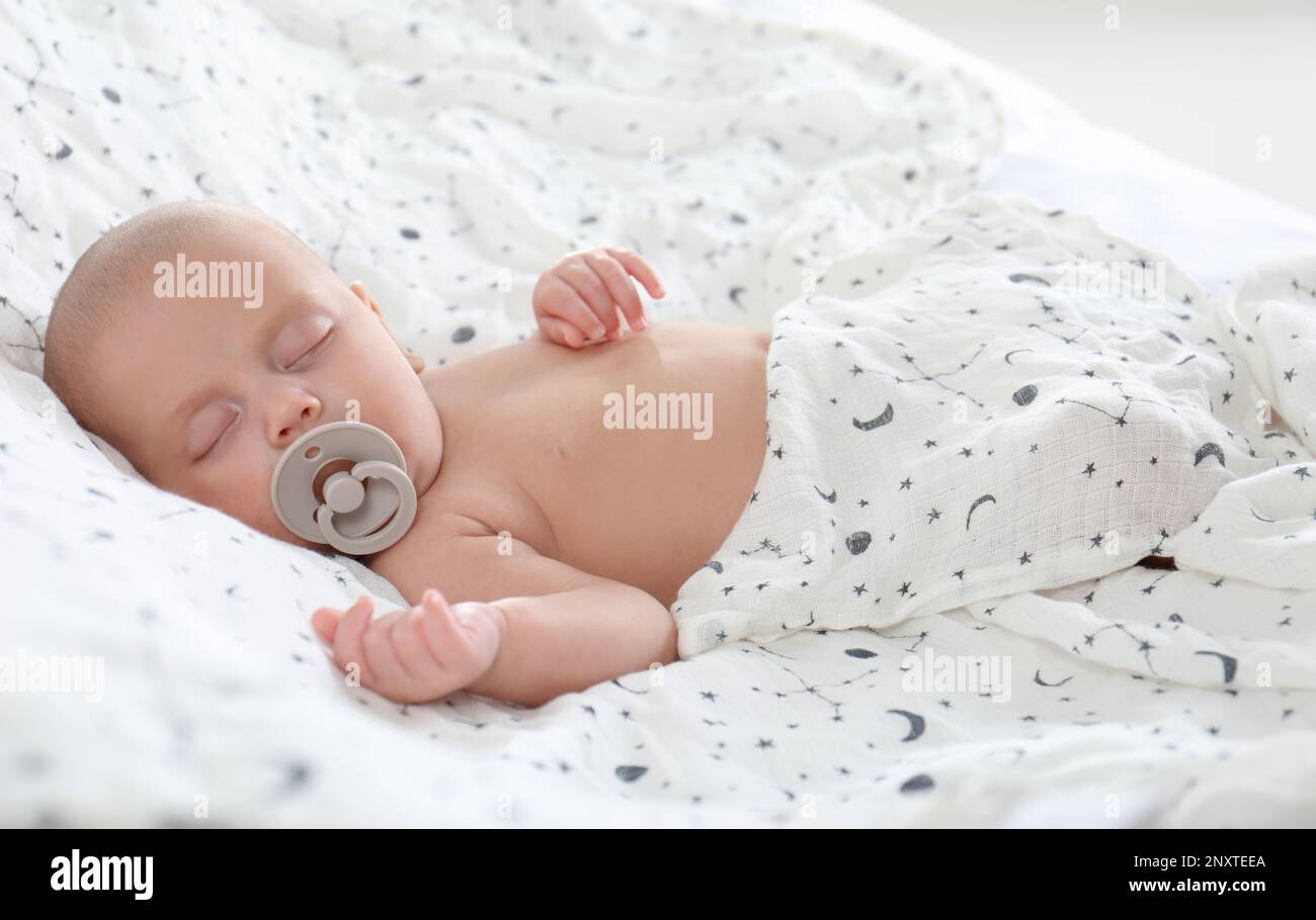 Cute little baby with pacifier sleeping on bed Stock Photo - Alamy