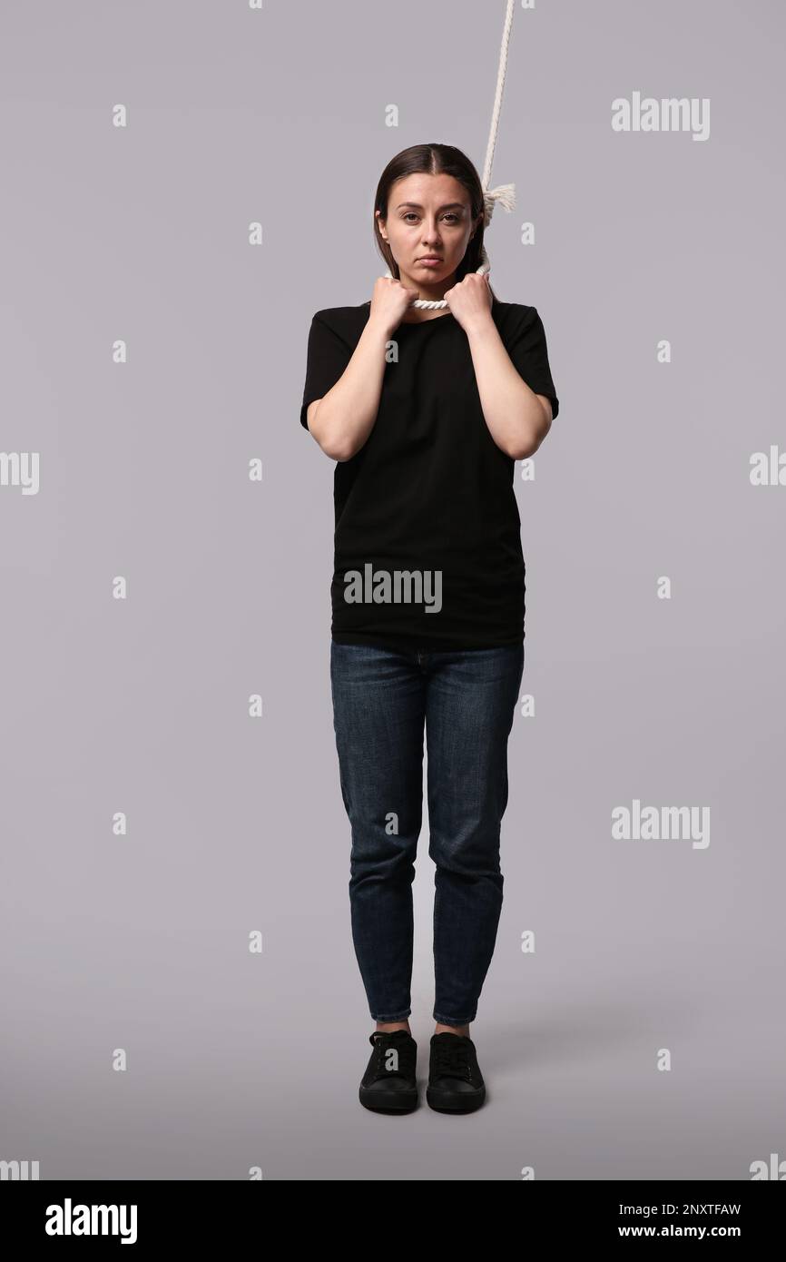 Depressed woman with rope noose on neck against light grey background ...