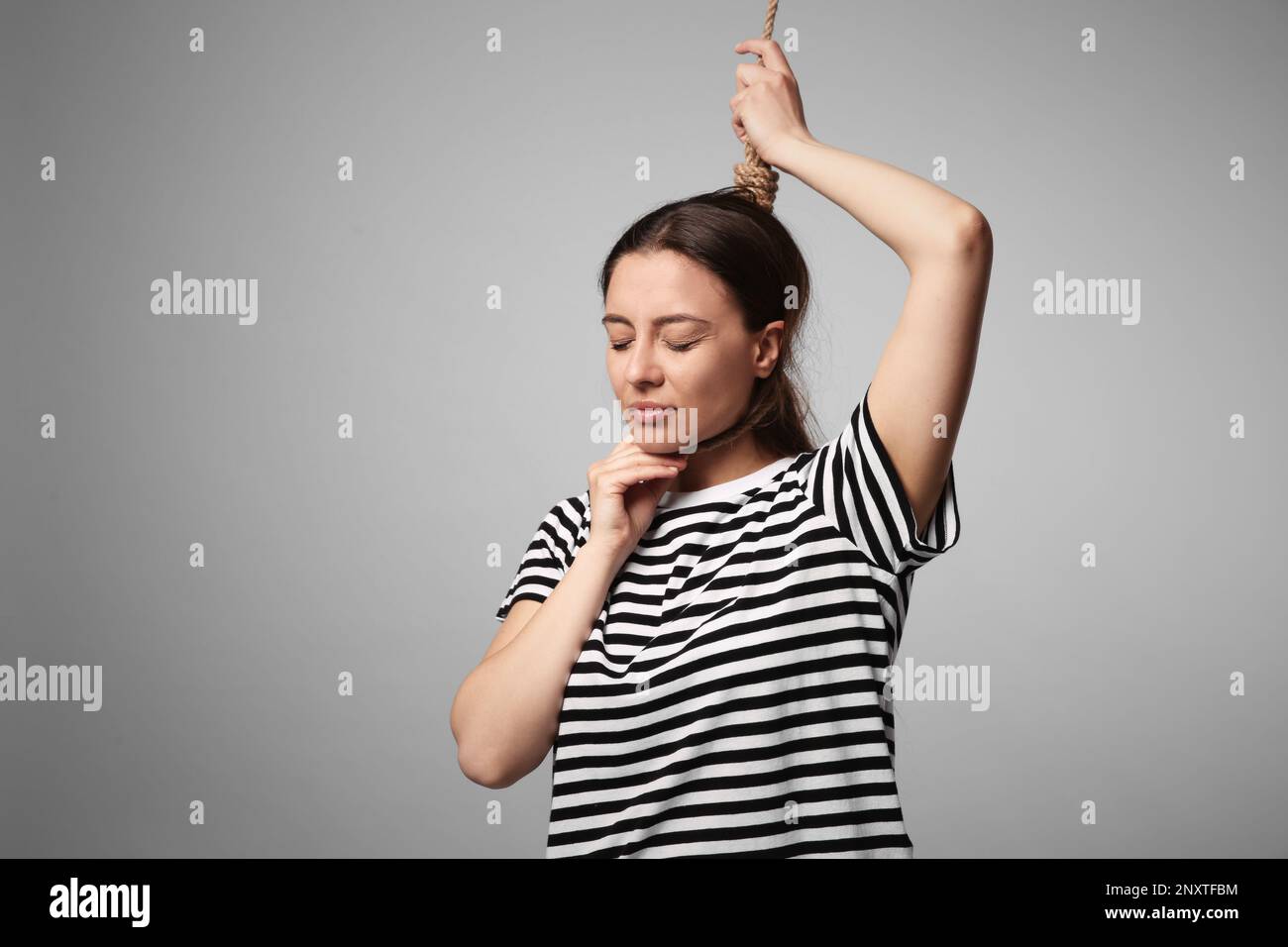 Depressed woman with rope noose on neck against light grey background ...