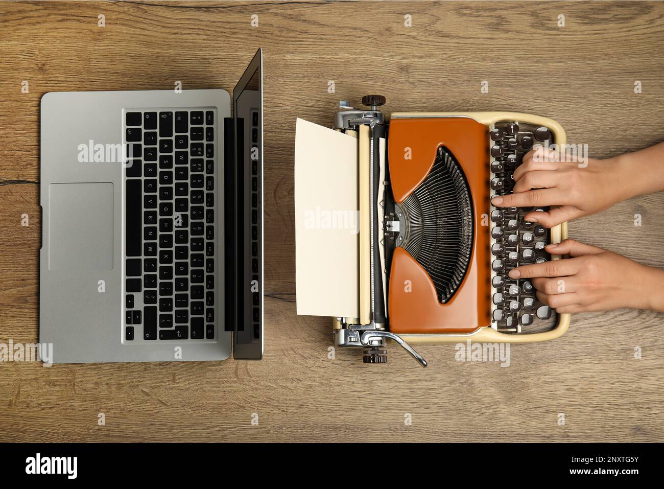 Woman using old typewriter near laptop at wooden table, top view ...