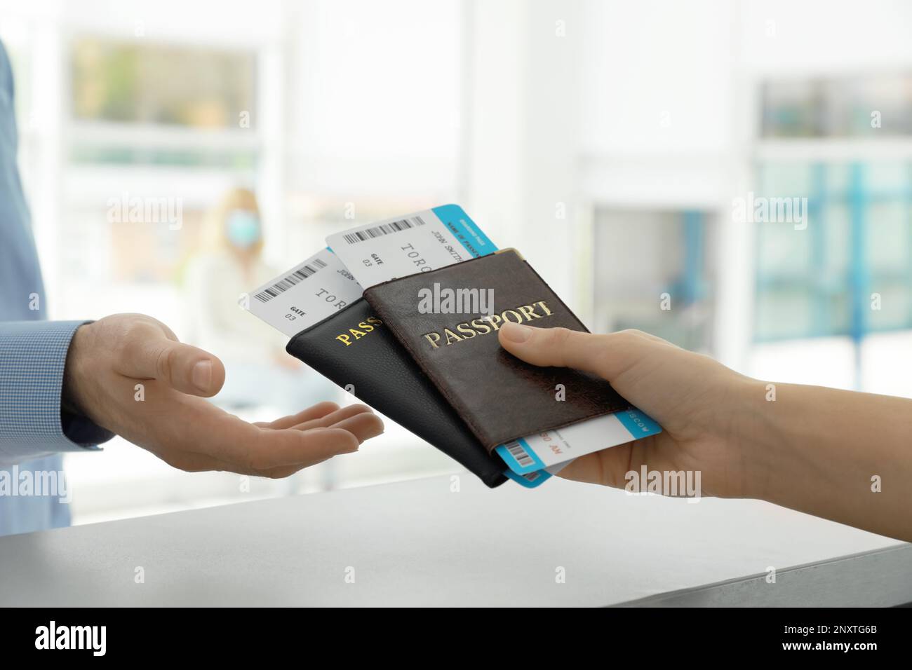 Agent giving passports and tickets to man at check-in desk in airport ...
