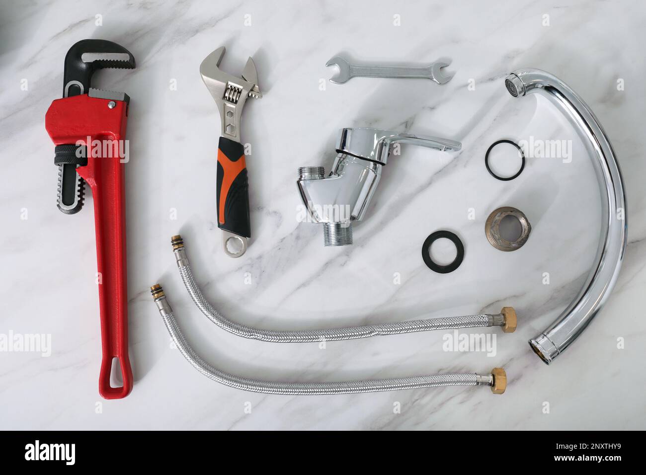 Parts of water tap and wrenches on white marble countertop, flat lay ...