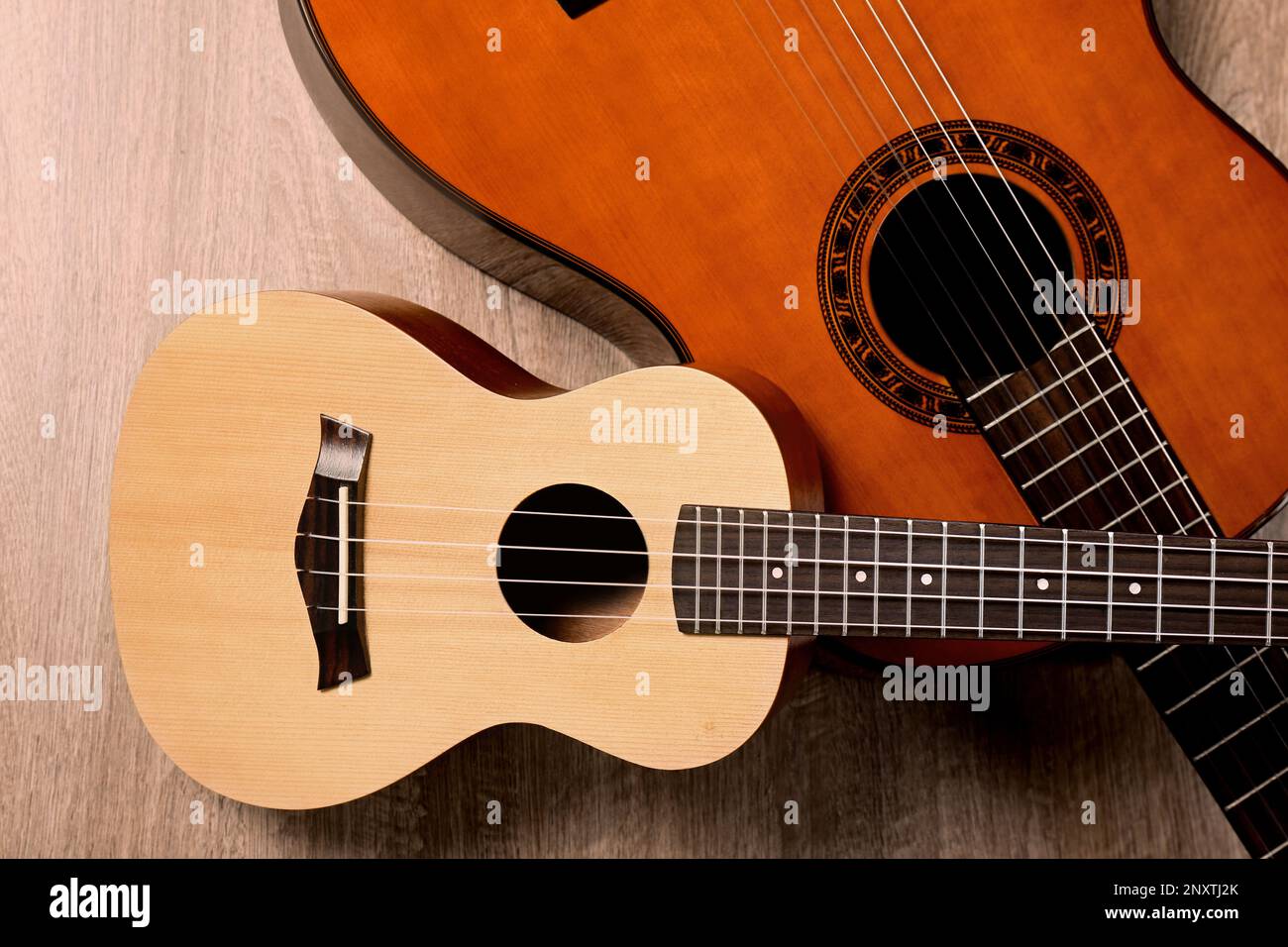 Ukulele and acoustic guitar on wooden background, flat lay. String ...