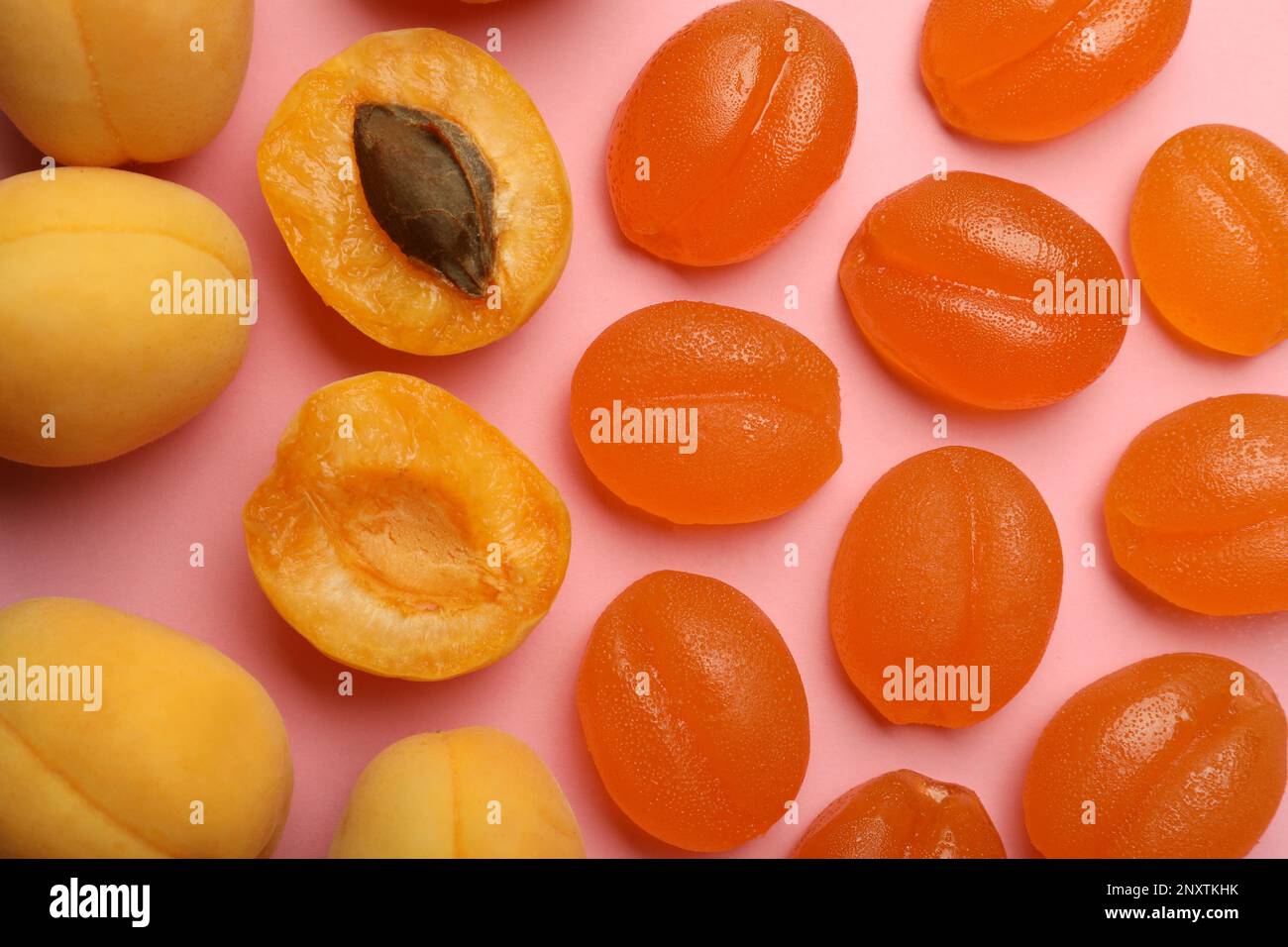 Delicious gummy apricot candies and fresh fruits on pink background ...