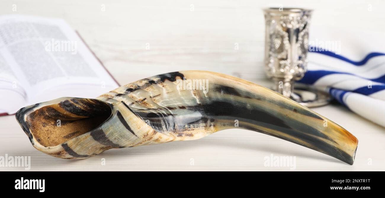 Shofar and other Rosh Hashanah holiday attributes on white wooden table ...