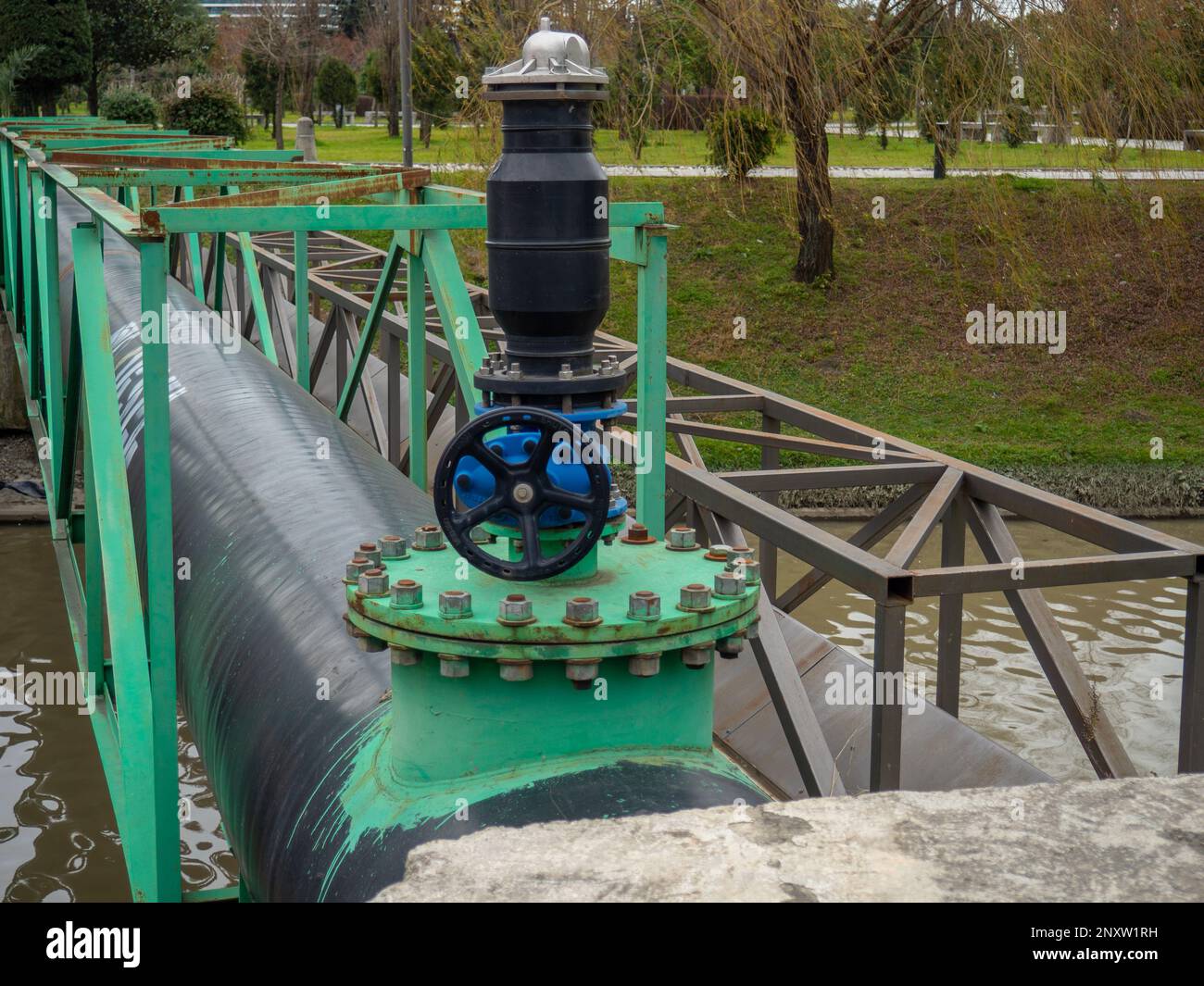 A valve on a large black pipe. Oil pipeline on the bridge ...