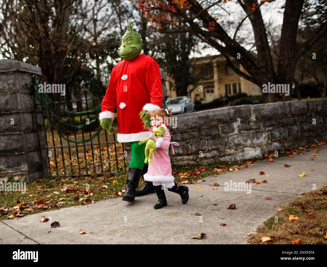 Charles Motley, dressed as the Grinch, walks with his granddaughter ...