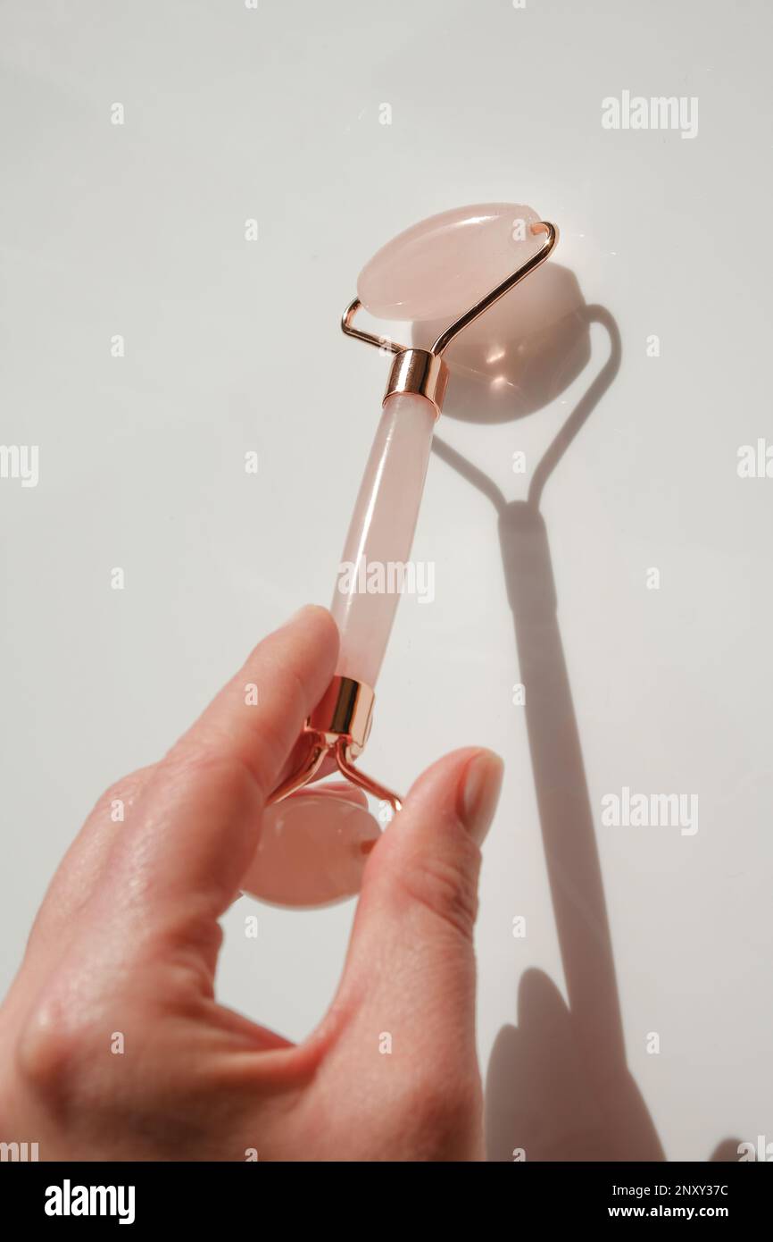 gua sha roller in a female hand on a light background.beauty devices ...