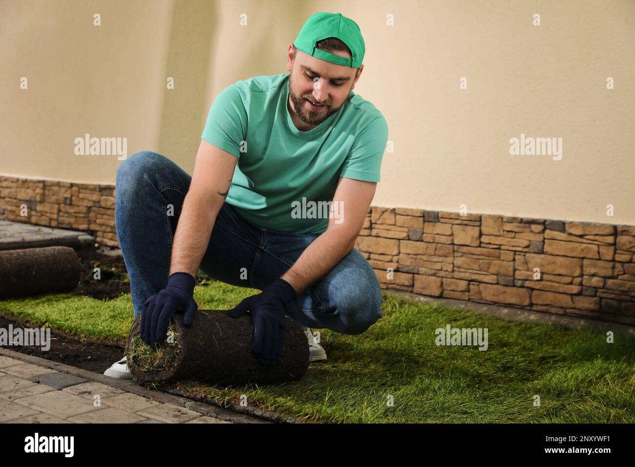 Worker laying grass sod on ground at backyard Stock Photo - Alamy
