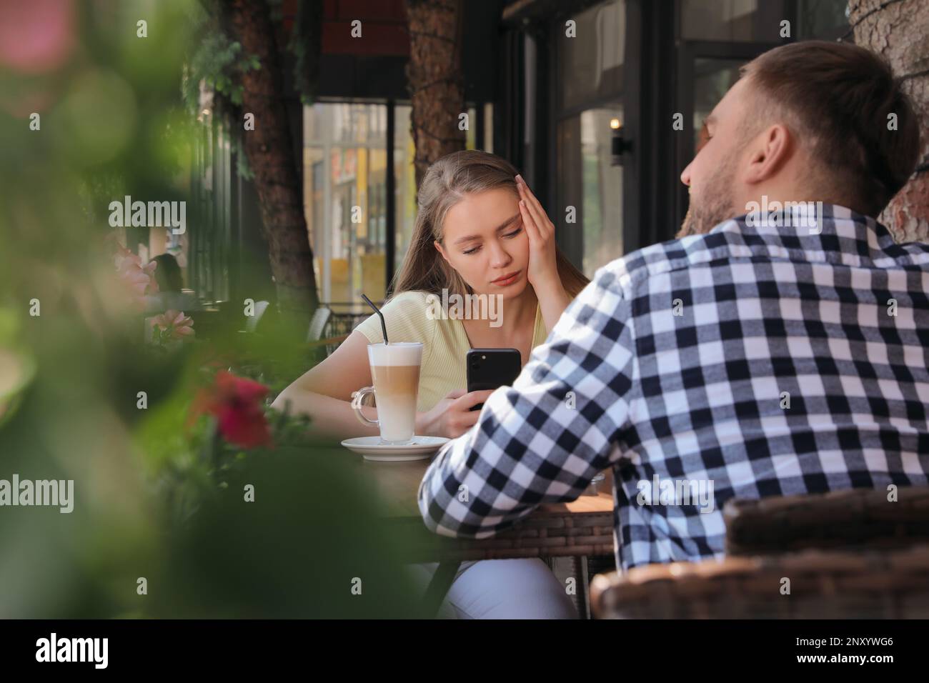 Young woman distracting herself with smartphone during boring date in ...