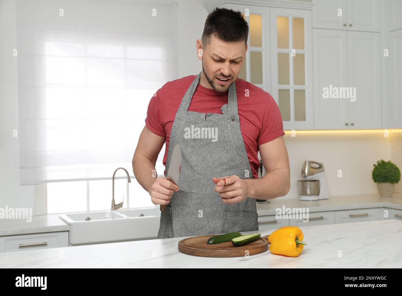 Man cut finger with knife while cooking at white marble table in ...