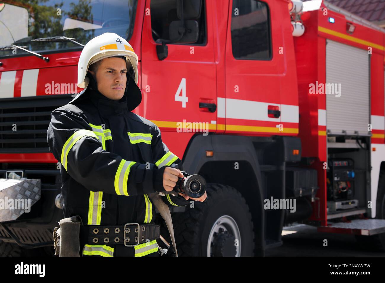 Firefighter in uniform with high pressure water jet near fire truck ...