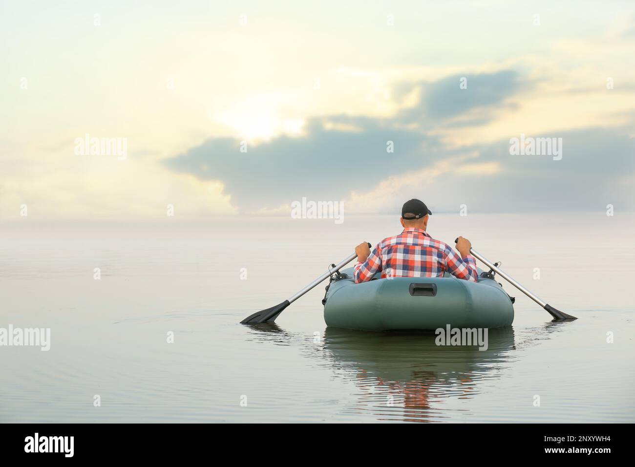 Man rowing inflatable rubber fishing boat on river, back view. Space ...