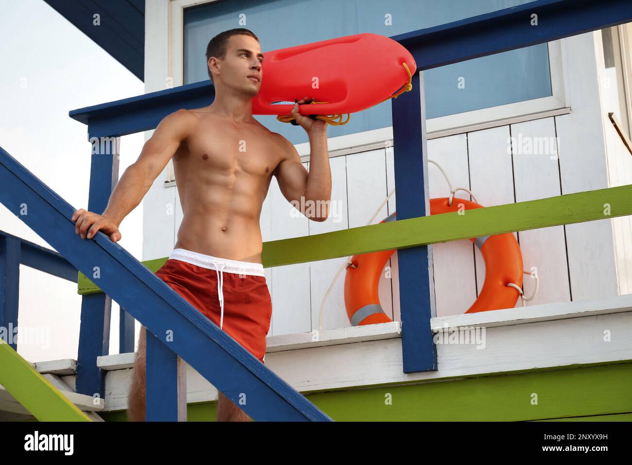 Handsome lifeguard with life buoy on watch tower Stock Photo - Alamy