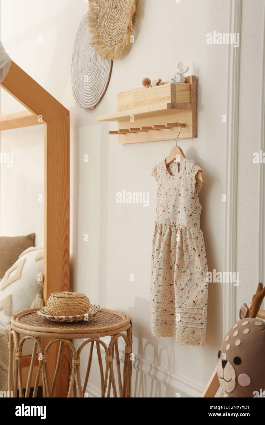 Wooden rack with cute dress in child room. Interior design Stock Photo ...