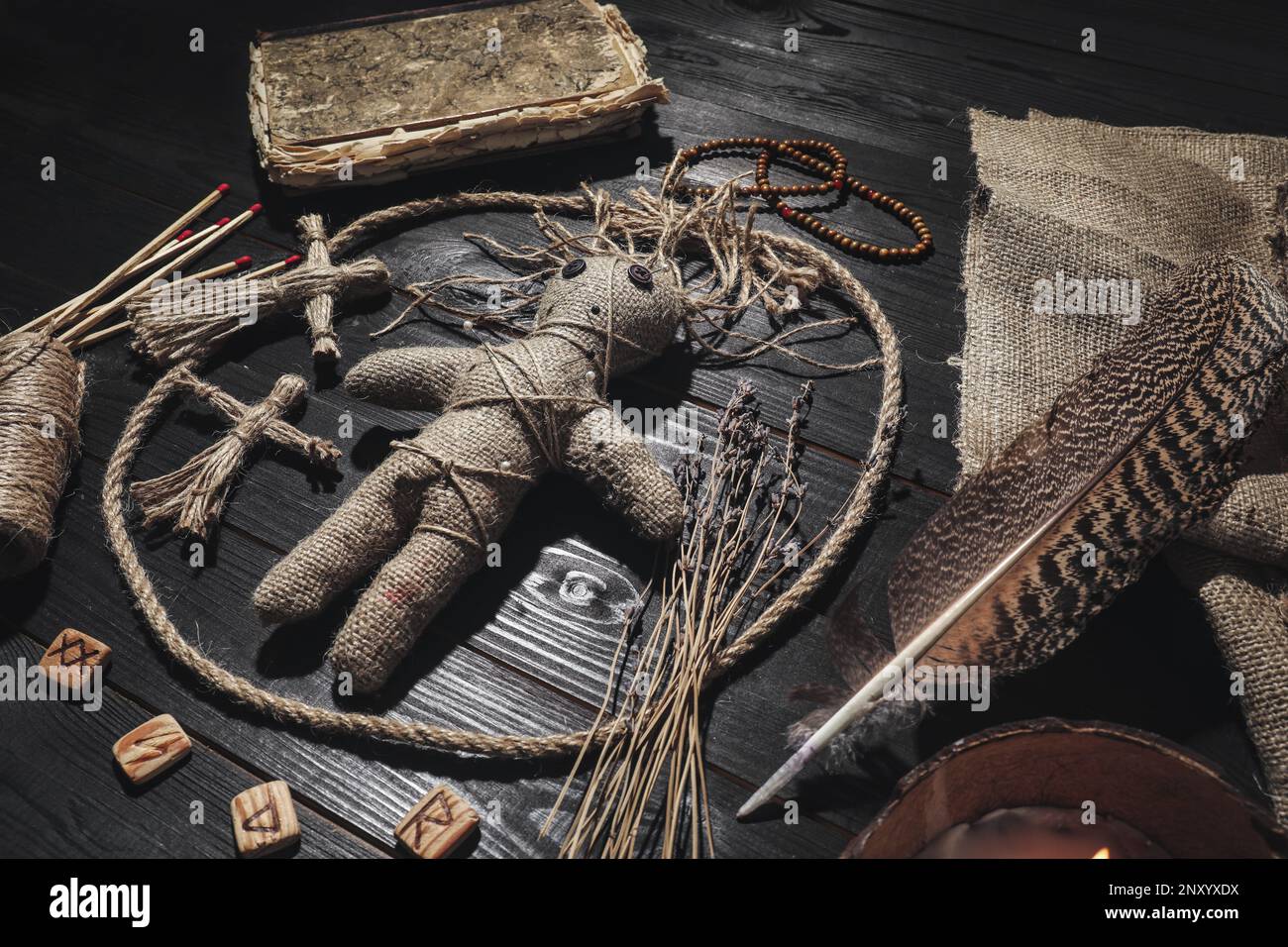 Female voodoo doll with pins surrounded by ceremonial items on black ...