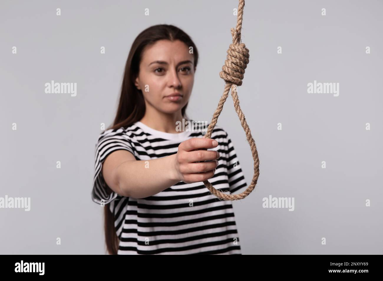 Depressed woman with rope noose on light grey background Stock Photo ...