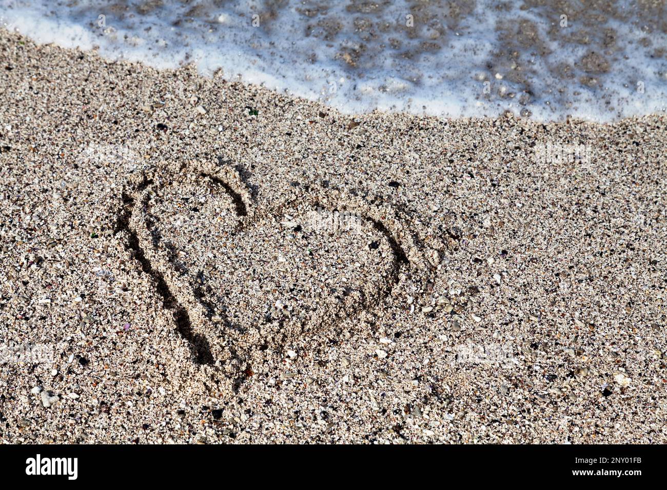 Heart drawn in the sand of the beach of Saint-Pierre de la Reunion with ...
