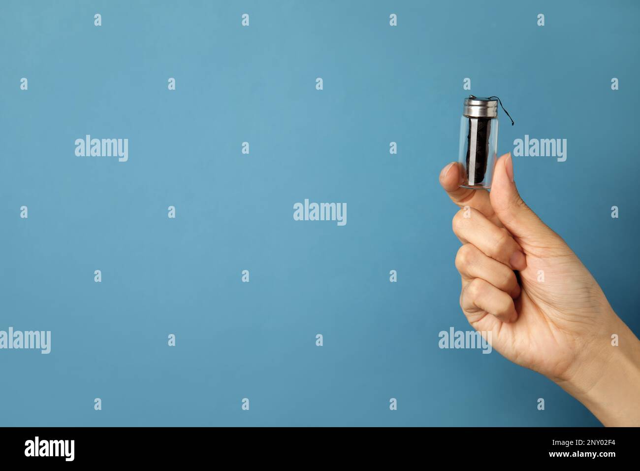 Woman holding glass jar with biodegradable dental floss against light ...