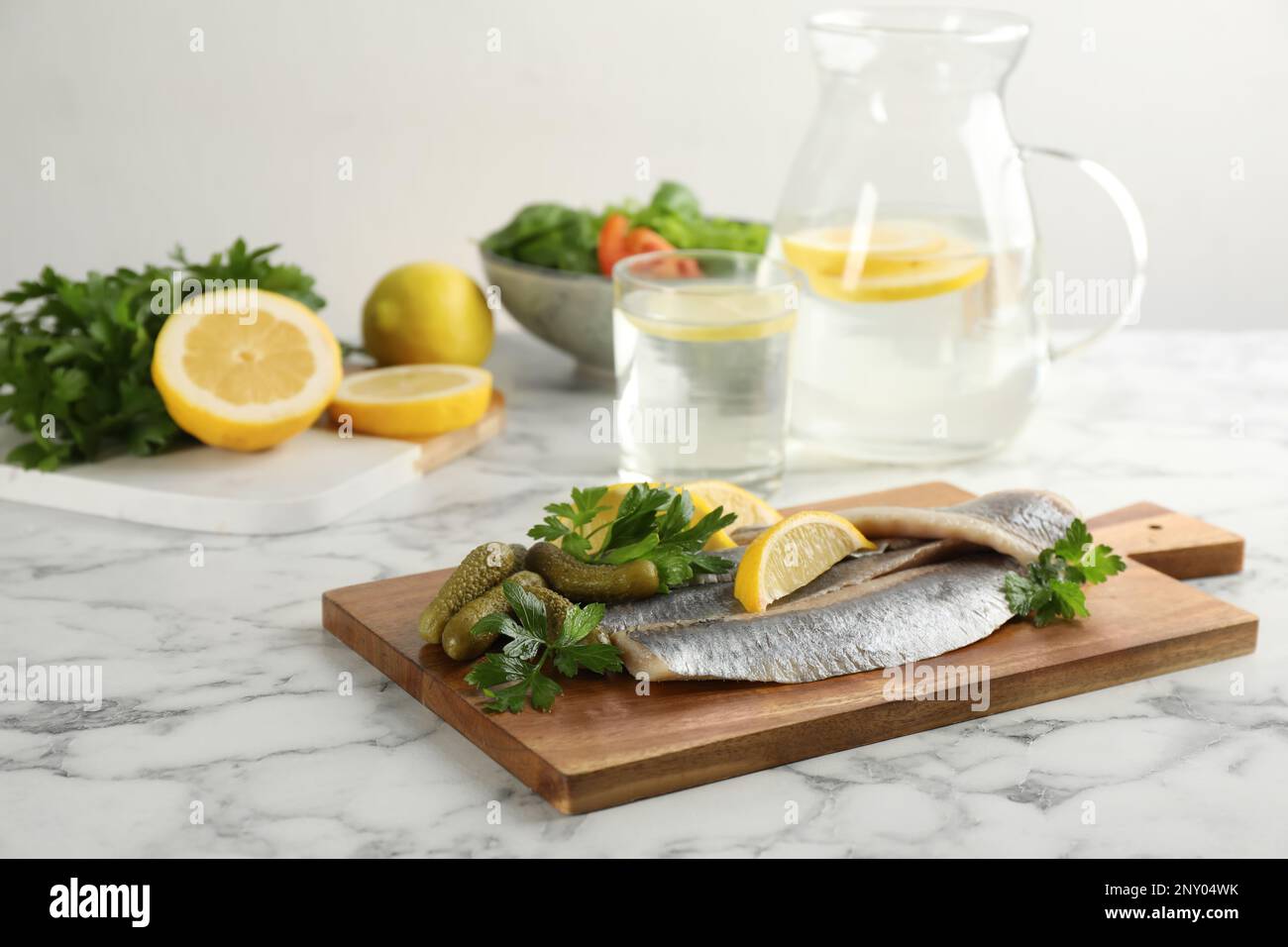 Salted herring fillets served with pickles, parsley and lemon on white ...
