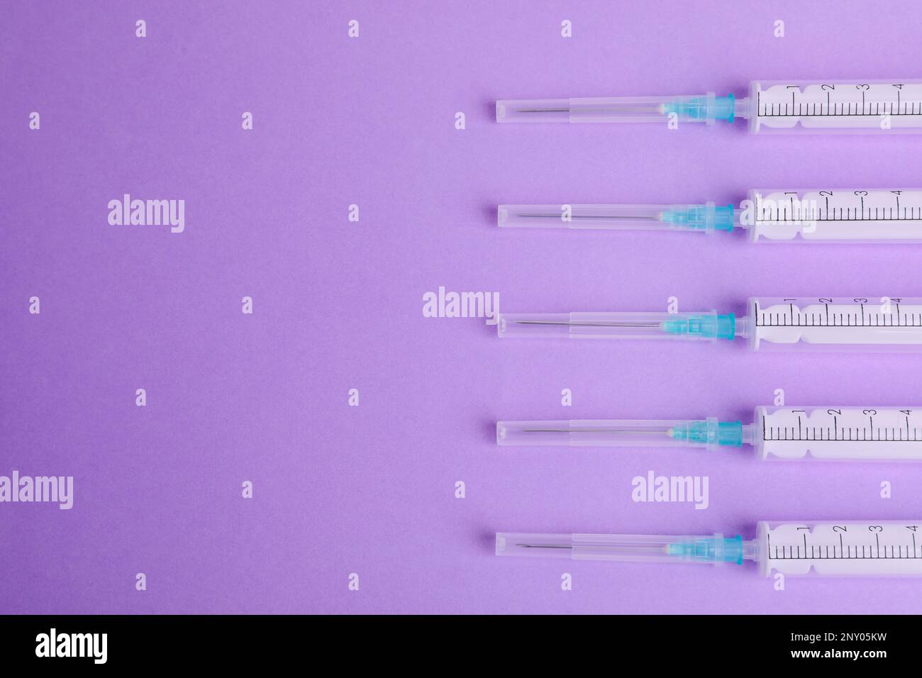 Disposable syringes with needles on violet background, flat lay. Space ...