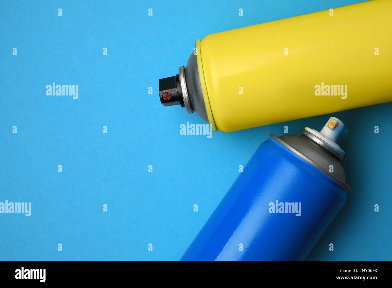 Cans of different graffiti spray paints on light blue background, flat ...