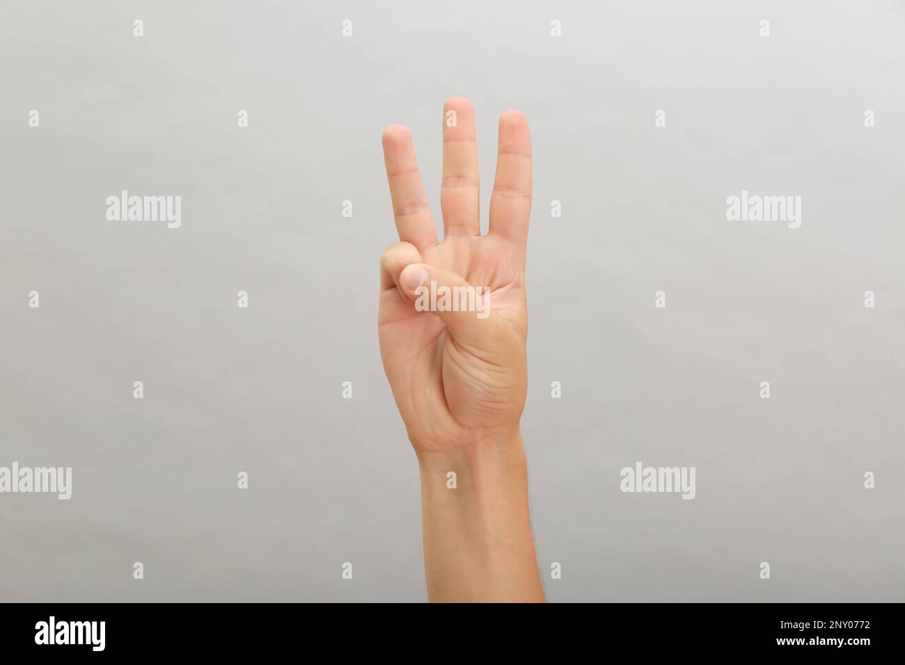 Teenage boy showing three fingers on light background, closeup Stock ...