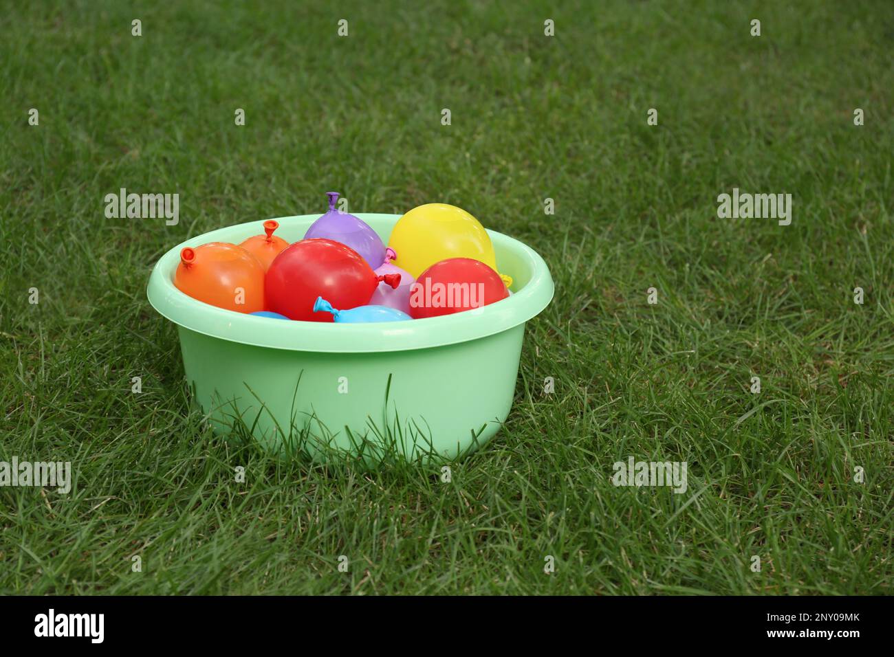 Basin full of water bombs on green grass. Space for text Stock Photo ...