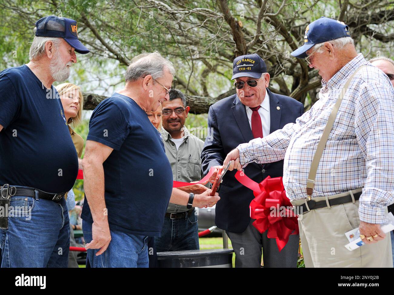 Ken Jarvis, wearing a USS Ranger hat, cuts a ceremonial ribbon at an ...