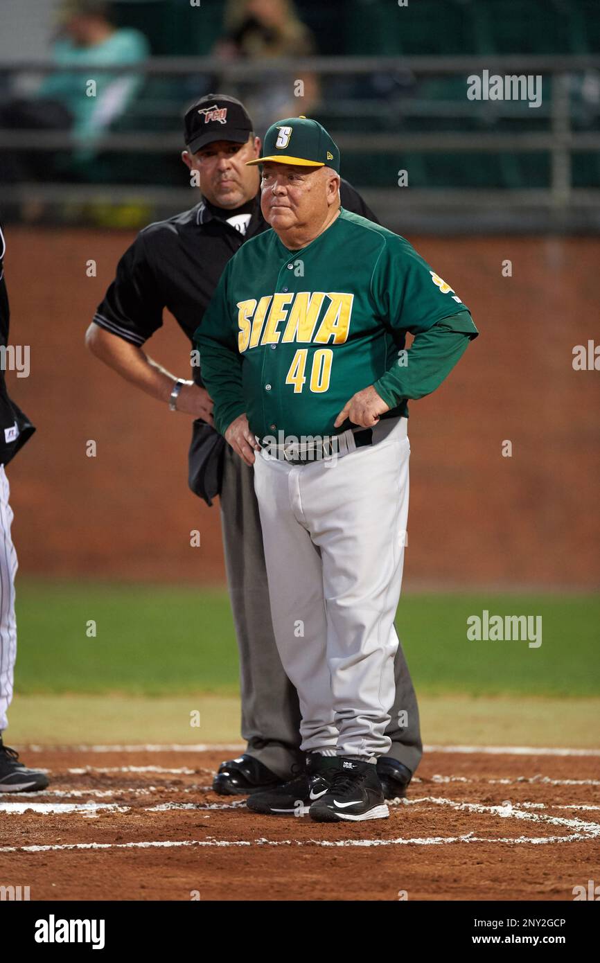Umpire Ray Parrish looks over the shoulder of Siena Saints head coach ...