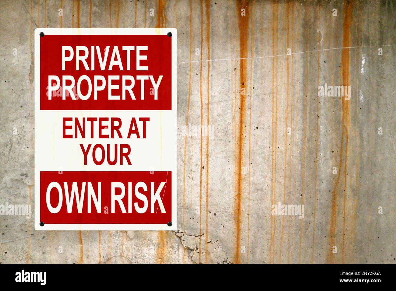 White and red sign screwed to a concrete wall. In the middle of the ...