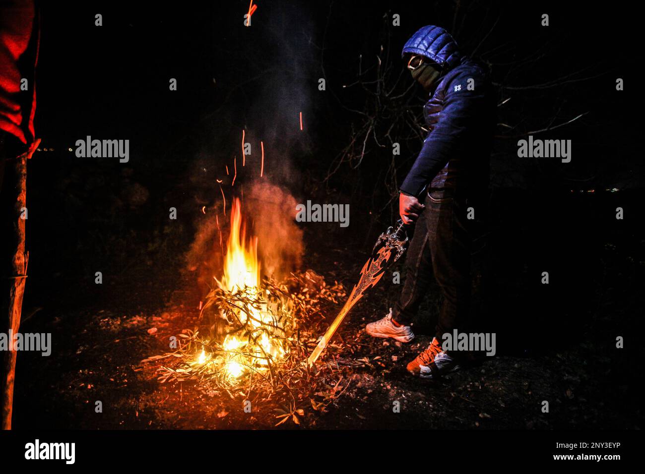 Masked Palestinians carrying wooden sticks around the fire stand on ...