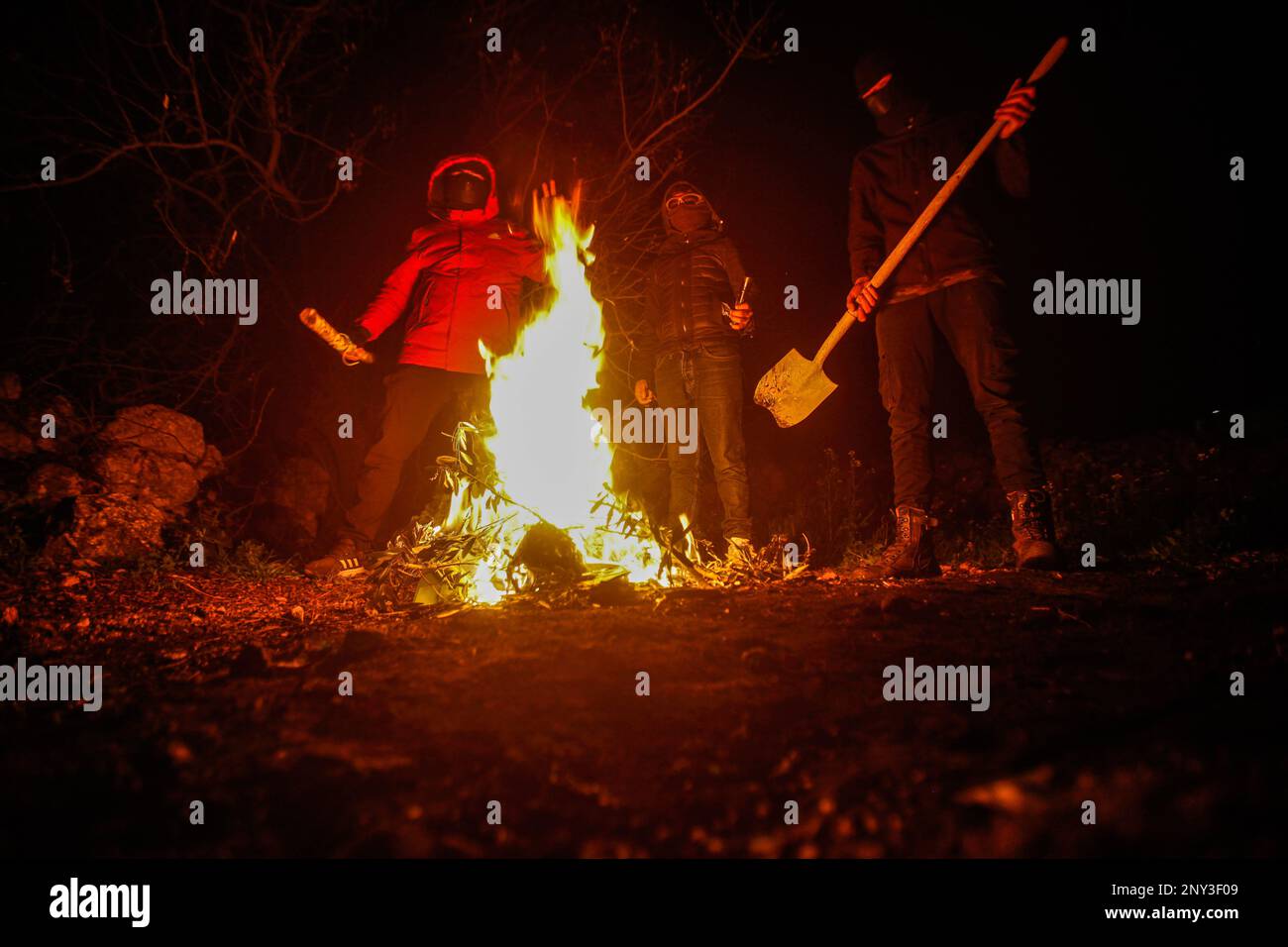 Masked Palestinians carrying wooden sticks around the fire stand on ...