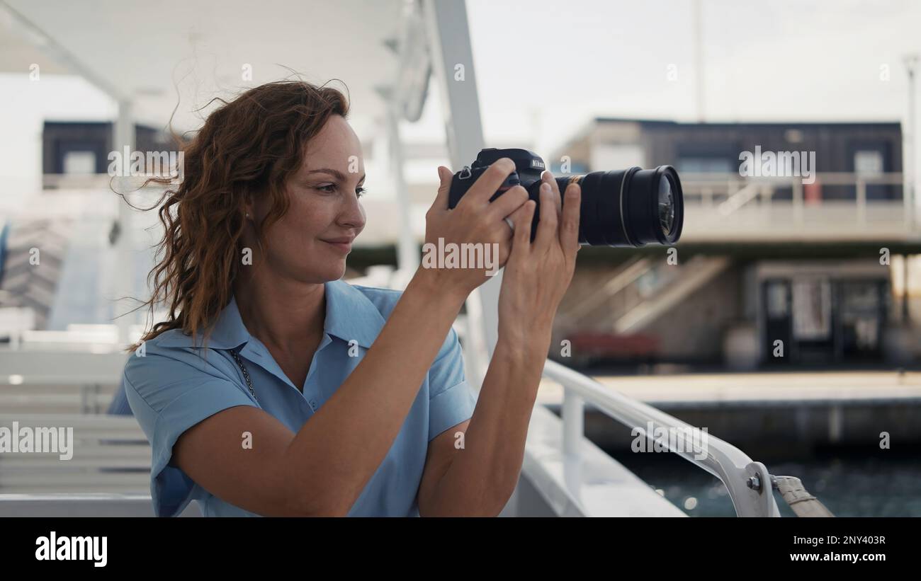 Beautiful woman taking pictures on the ship. Action. A young ...