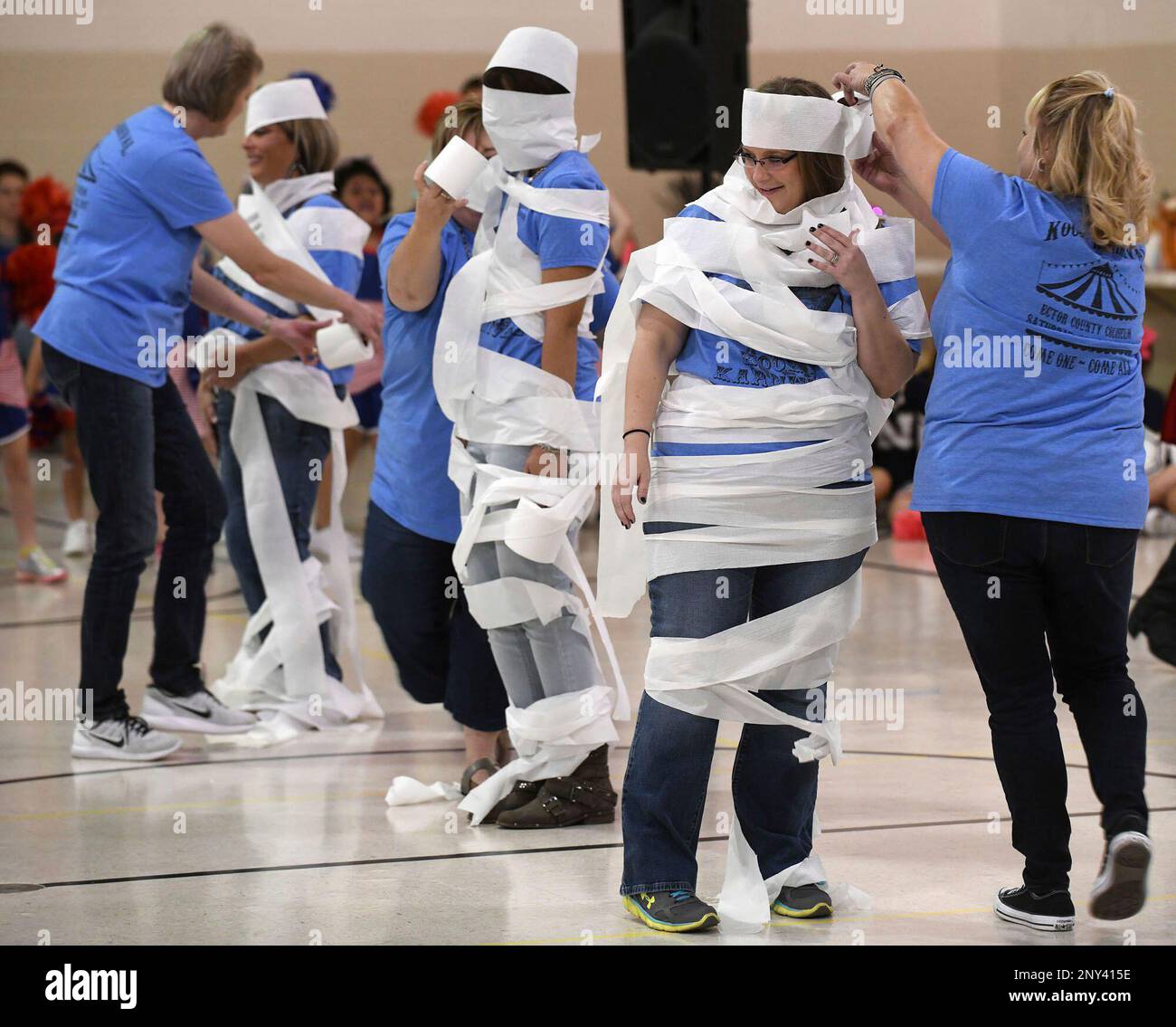 Teachers wrap their team partners in toilet paper in a contest during ...