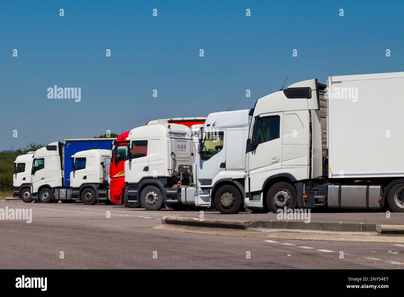 Row of cab over semi-trailer trucks parked in a highway parking lot ...