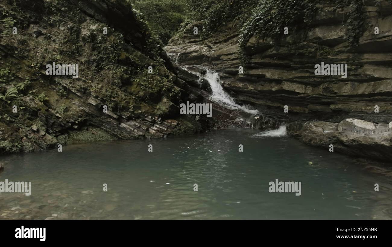 Cold clean waterfall in the mountains. Creative. A beautiful pond where ...