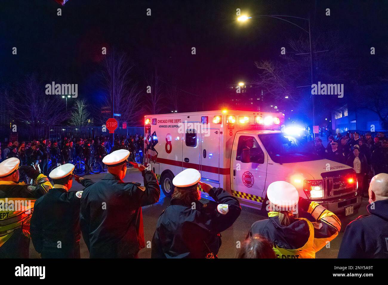 Chicago police officers and firefighters salute a procession carrying ...