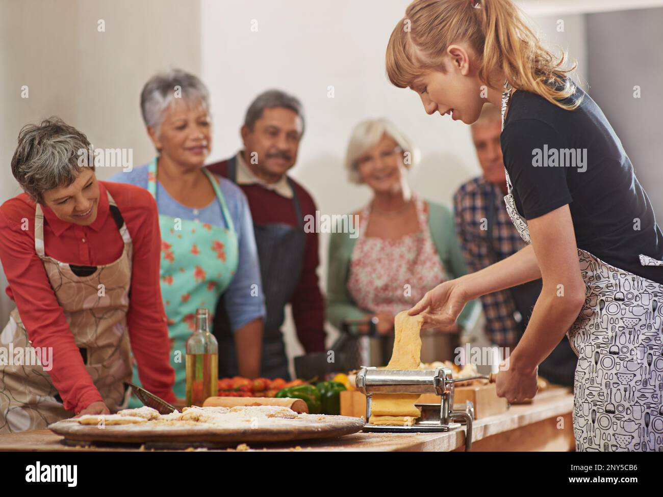 Getting the pasta dish rolling. a woman showing her class how to make ...