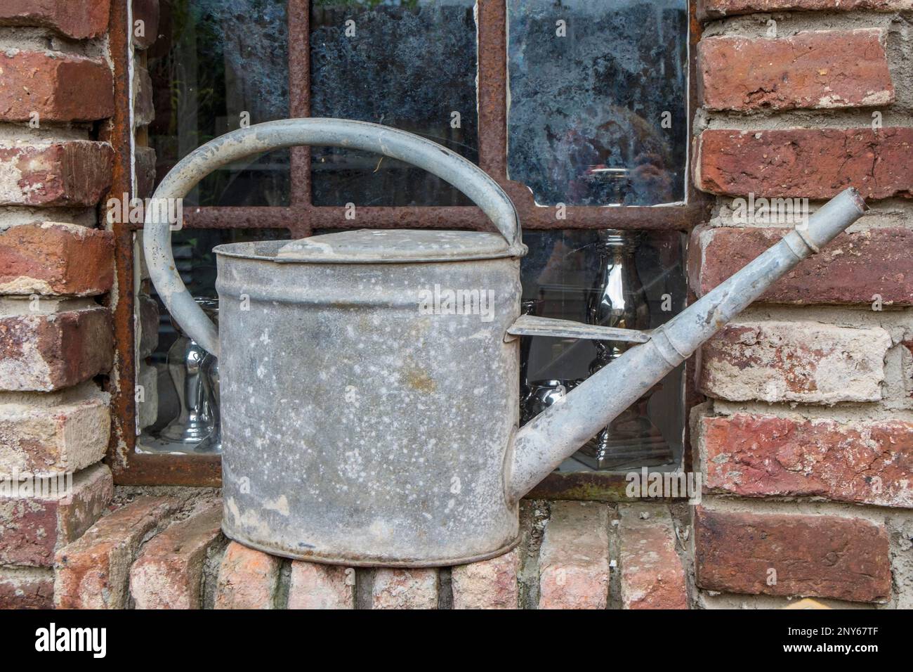 Old watering can in front of stable window Stock Photo - Alamy